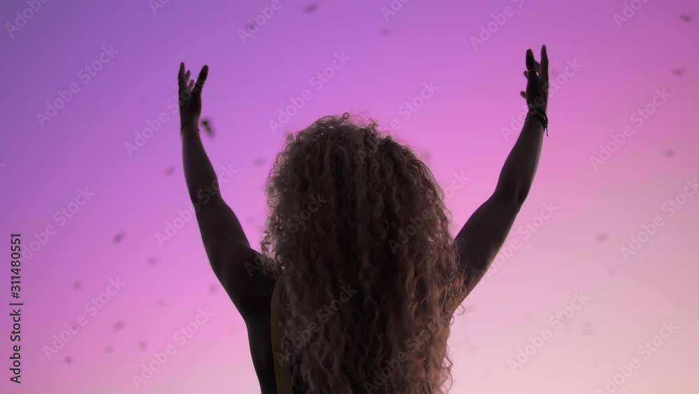 A woman with long blonde, curly hair with arms stretched out to the ...