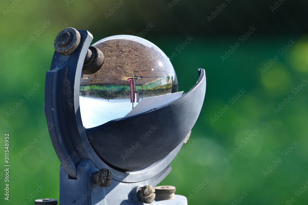 Weather station and the sun in a blue sky reflected in the glass sphere ...