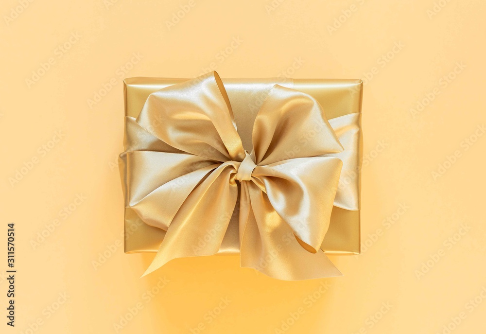 Festive background with gold gift, gift box with ribbon and bow on gold ...