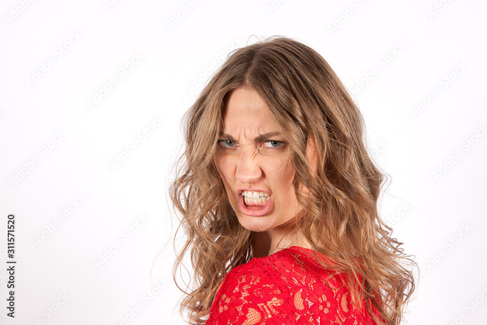 Angry woman in red dress portrait on a white background with grin teeth ...