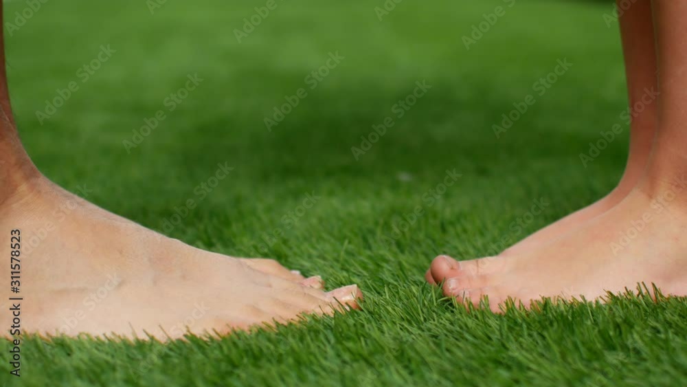 Two barefoot people on the green grass. Step on each other's foot Stock ...