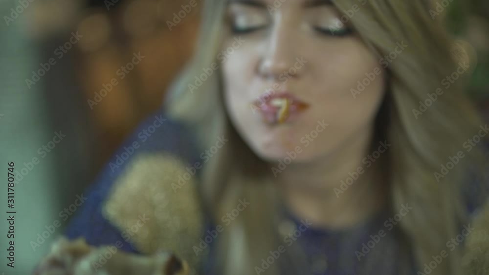 Angry greedy attractive blonde young woman biting huge pieces of meat ...