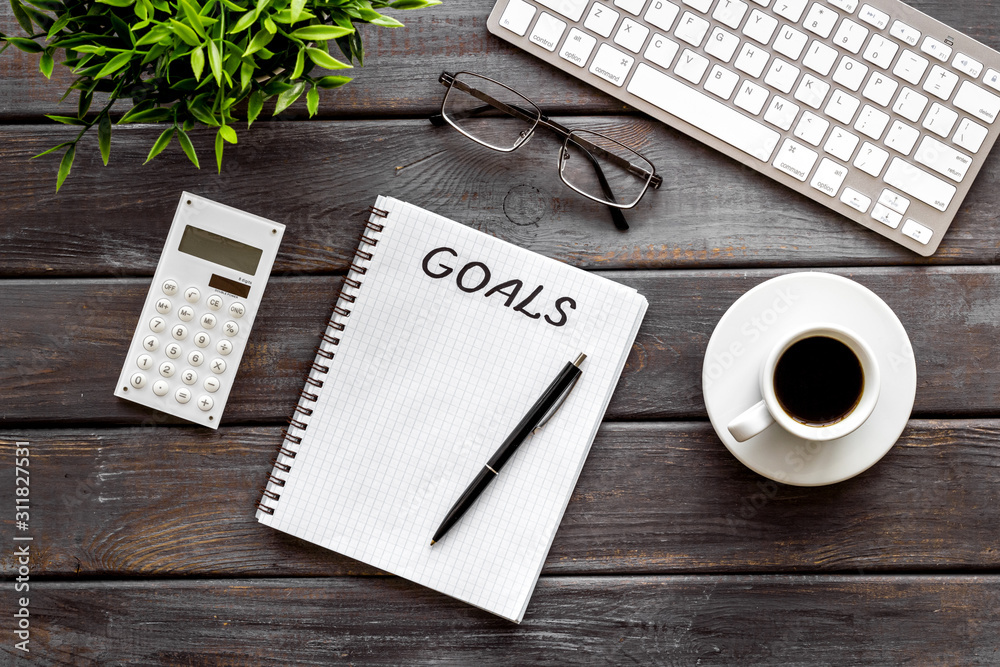 Plan concept. Goals text in blank notebook on dark wooden office desk ...