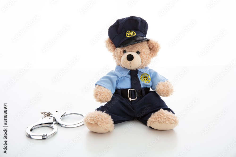 Cute teddy in policeman uniform and handcuffs isolated against white ...
