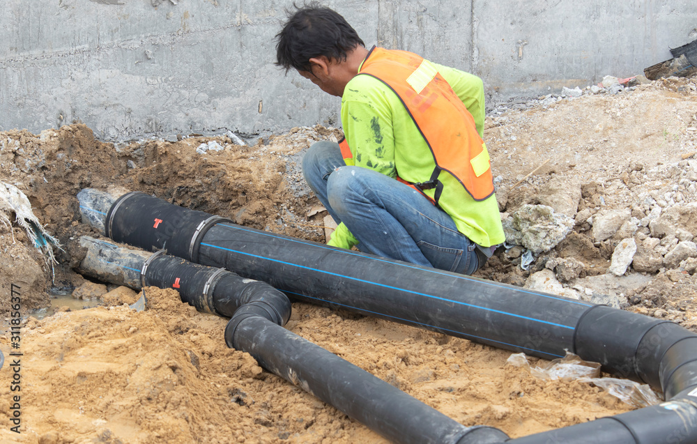In the construction area, the workers are installing the black pipe to ...
