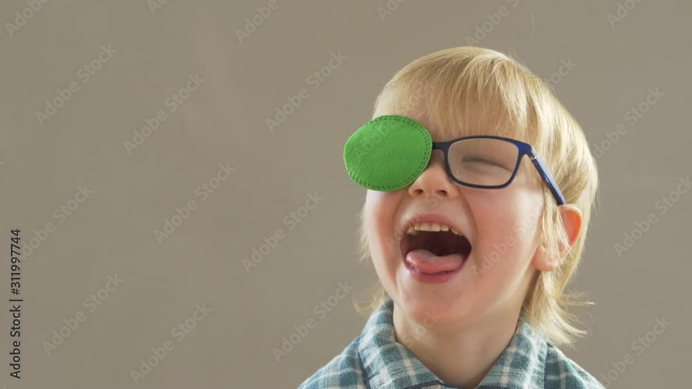 Portrait of funny child in new glasses with green spot to correct ...