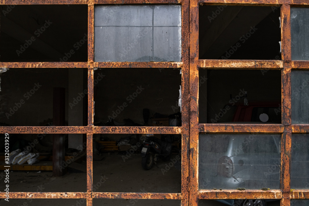 The broken windows and rusting frame of a door leading into a garage ...