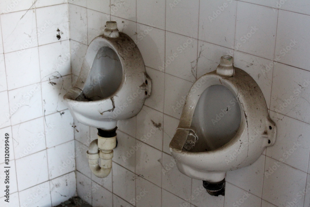 Two vintage retro old disconnected urinals covered with dust and cobweb ...