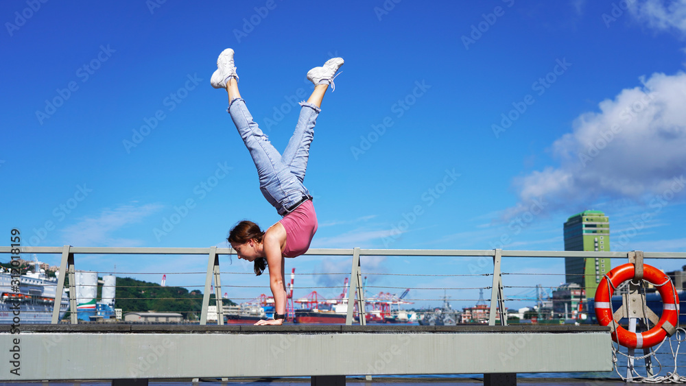 Young flexible girl in life style clothes makes a handstand on ...