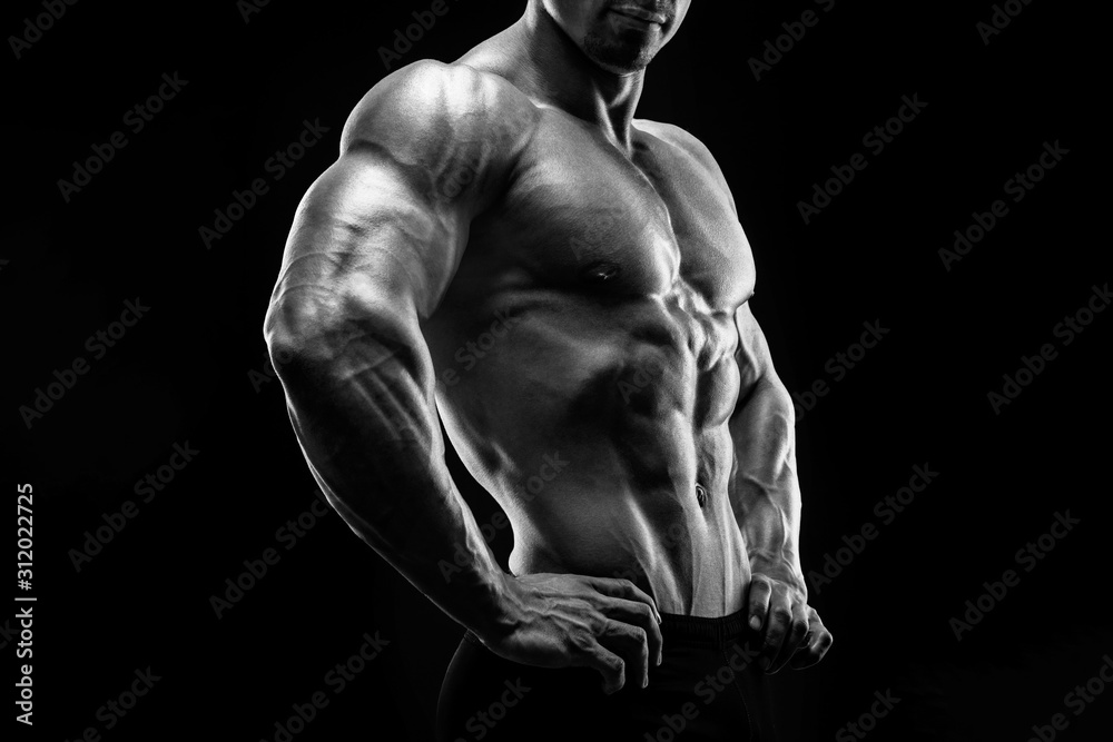 Muscular and fit young bodybuilder fitness male model posing over black ...