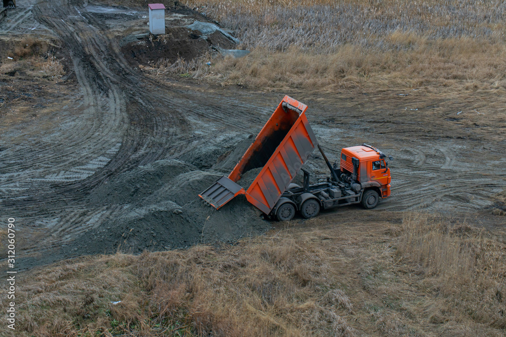 Industrial dumper truck working on highway construction site, loading ...