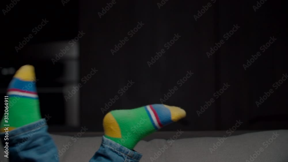 Kids legs in jeans and green socks shaking in the air with dark ...