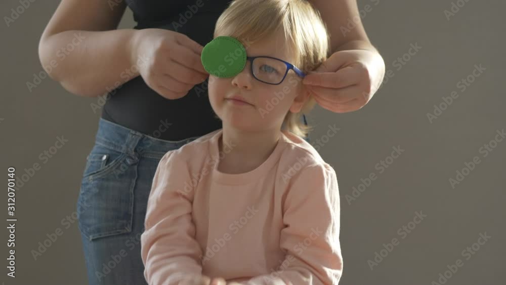 Portrait of funny child in new glasses with green spot to correct ...