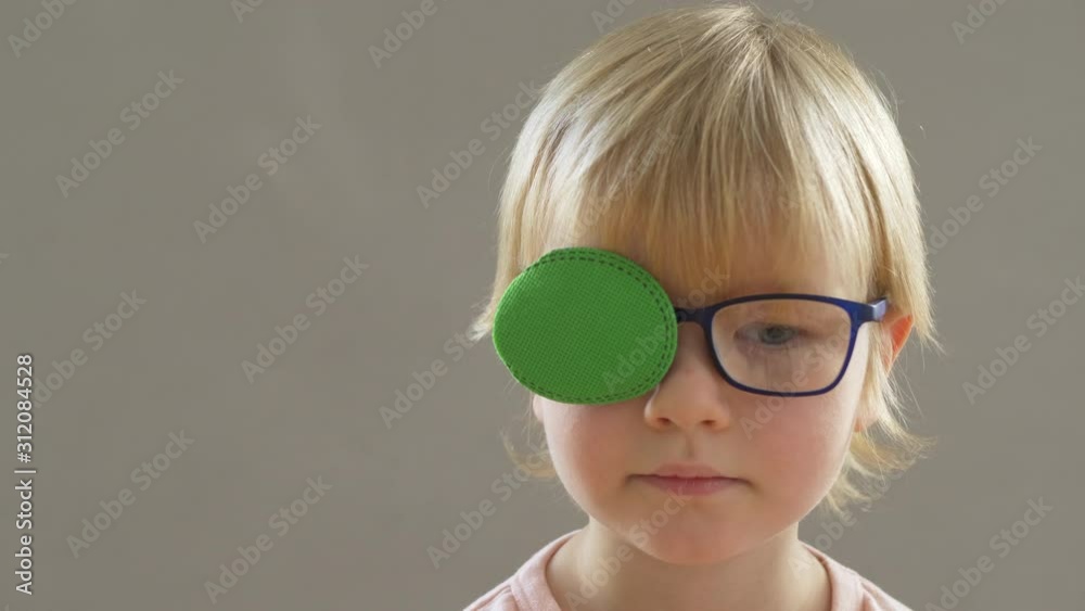 Portrait of funny child in new glasses with green spot to correct ...