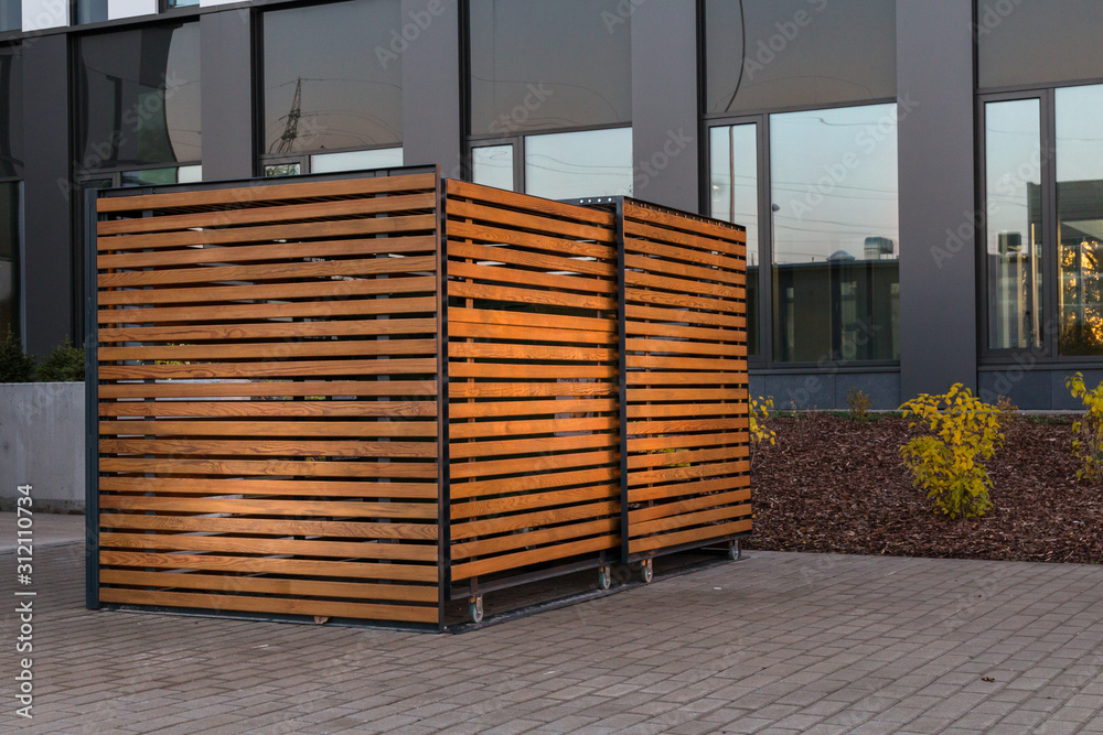 Dumpster containers hidden inside wooden cage Stock Photo | Adobe Stock