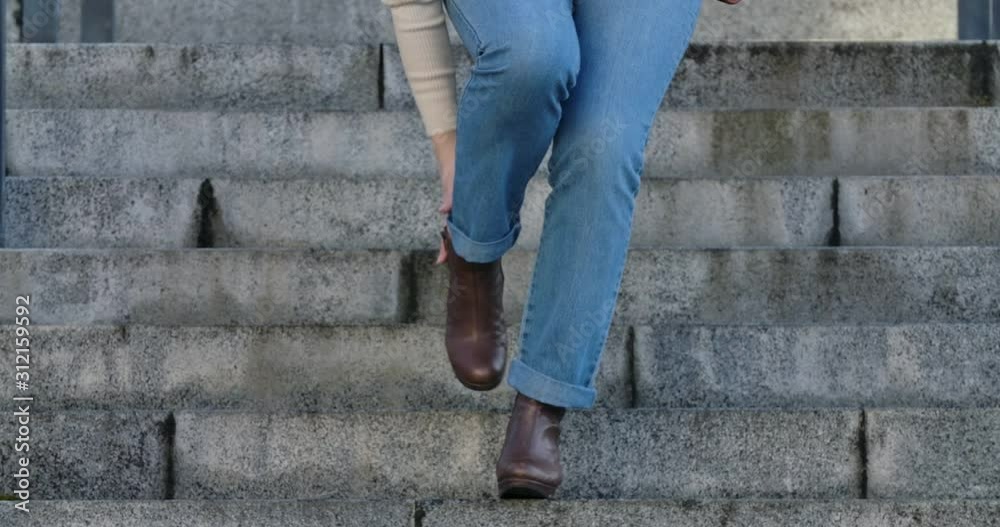 Close-up of female Caucasian legs stepping down the stairs and stopping ...
