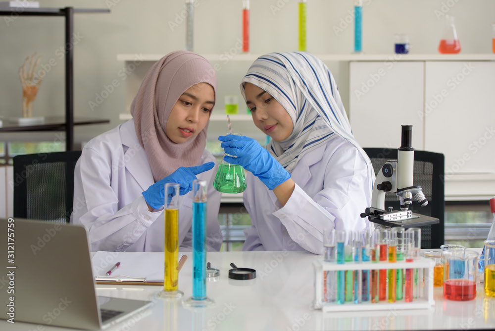 Muslim scientist female looking in experiment chemical liquid in ...