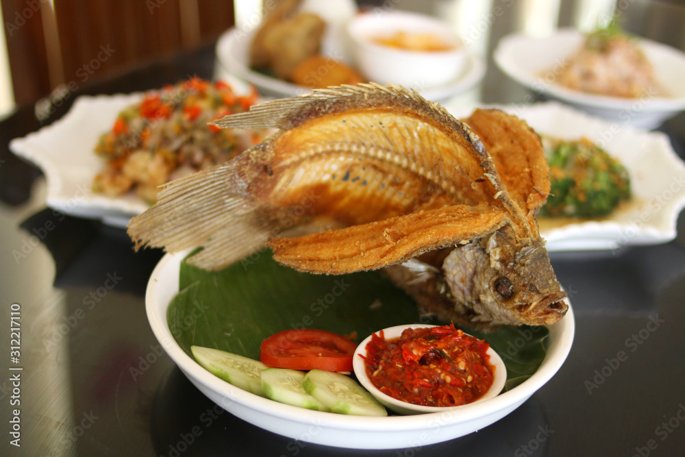 Flying fried fish served with chili sauce, cucumber and tomatoes from ...