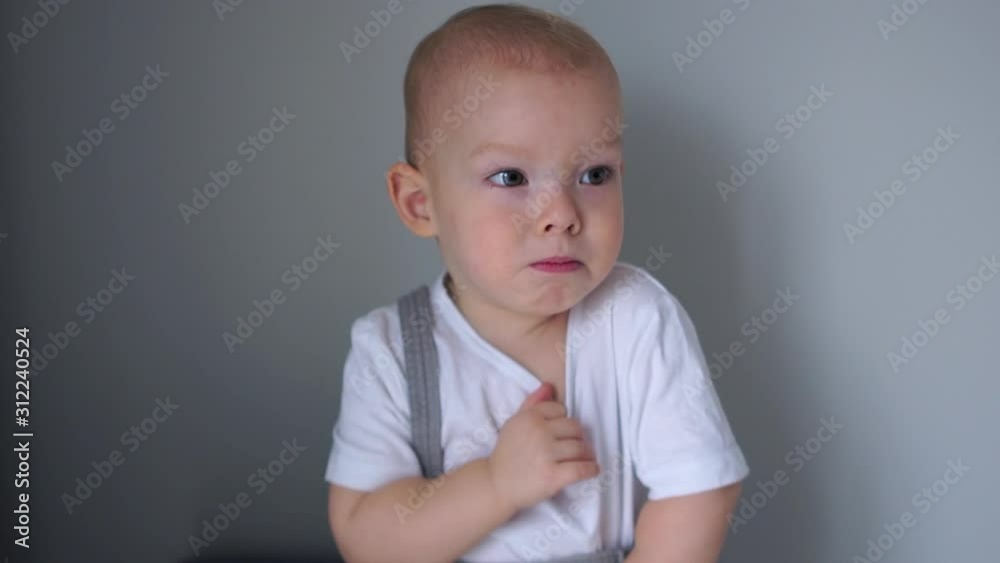 Portrait of the two-year blue-eyed boy in a white T-shirt. The boy is ...