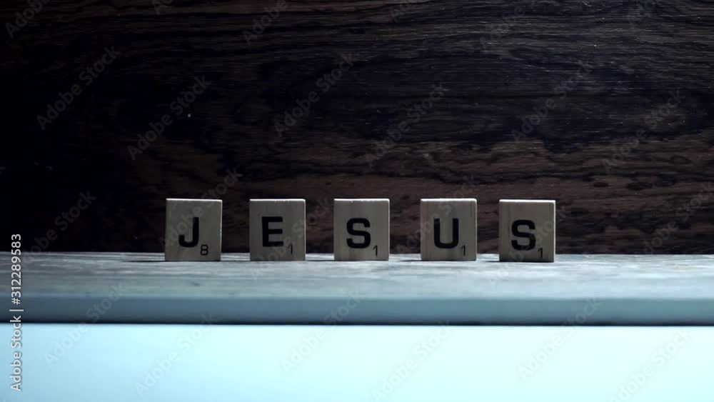 The word "JESUS" spelled out in wooden letters with overhead fluttering ...
