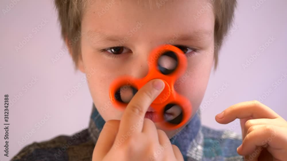 Funny blond child in striped shirt twists spinner on his nose. Portrait ...