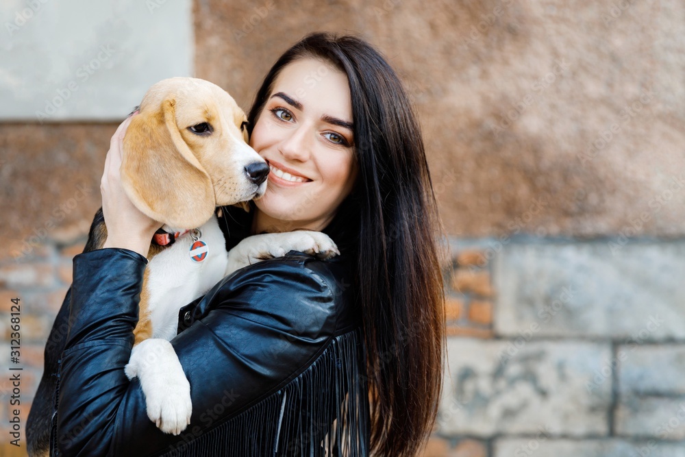 Pretty brunette girl takes in the arms of his beloved cute dog. Girl ...