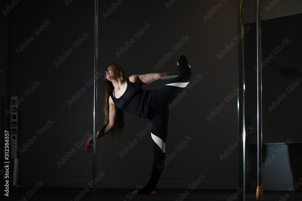 The dancer on the pylon in the studio. Girl doing exercises on a sports ...