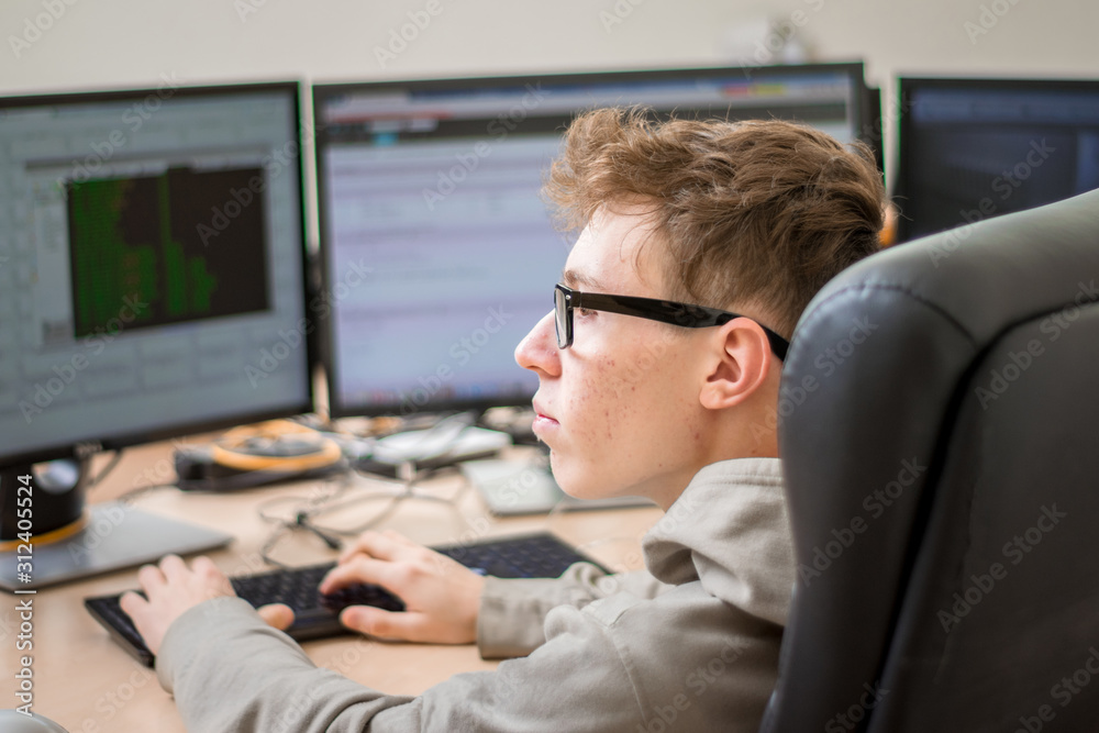 Male portrait in profile. Teenager looks at the monitor screens. Side ...
