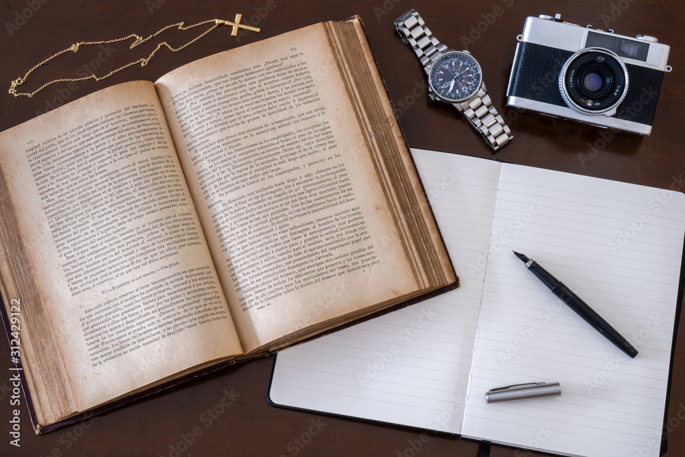 An old book, a notebook, a fountain pen, a watch, a cross and an analog ...