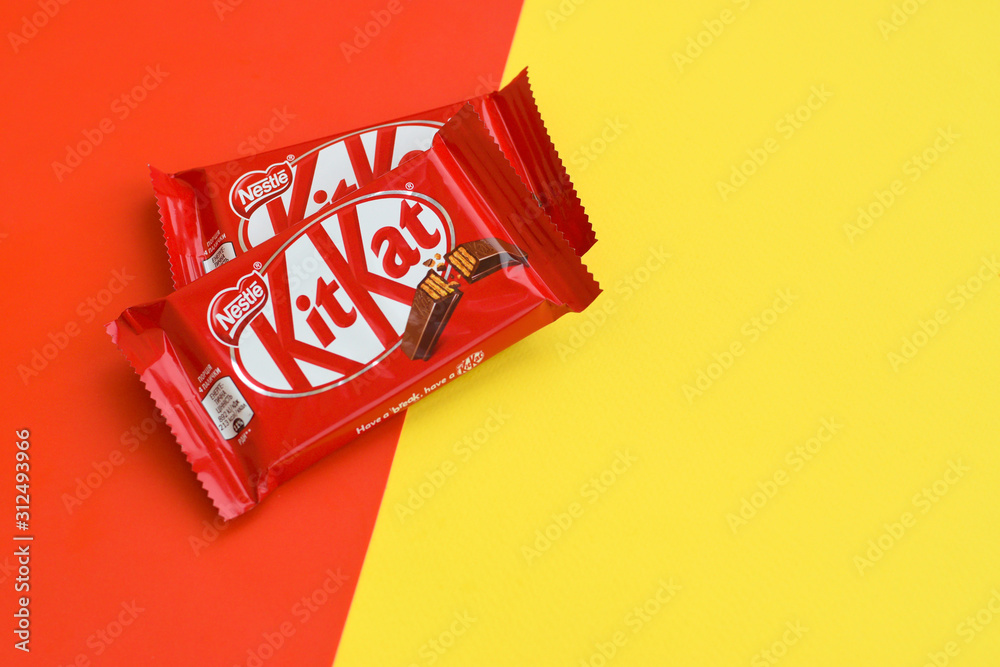 Kit Kat chocolate bars in red wrapping lies on yellow and red ...