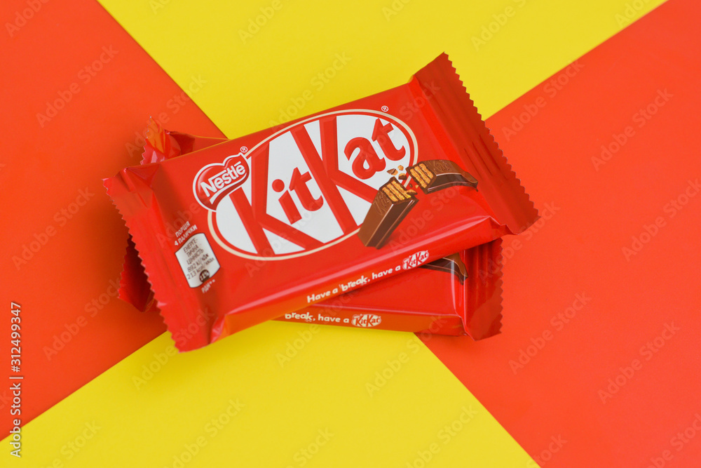 Kit Kat chocolate bars in red wrapping lies on yellow and red ...