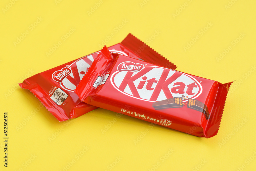 Kit Kat chocolate bar in red wrapping lies on yellow background. Kit ...