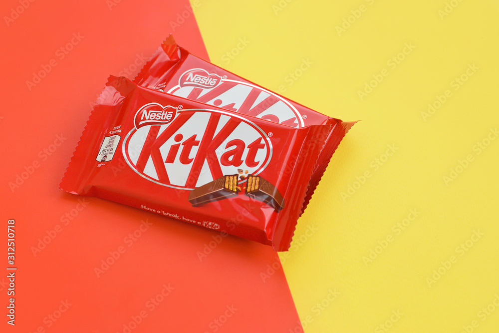 Kit Kat chocolate bars in red wrapping lies on yellow and red ...