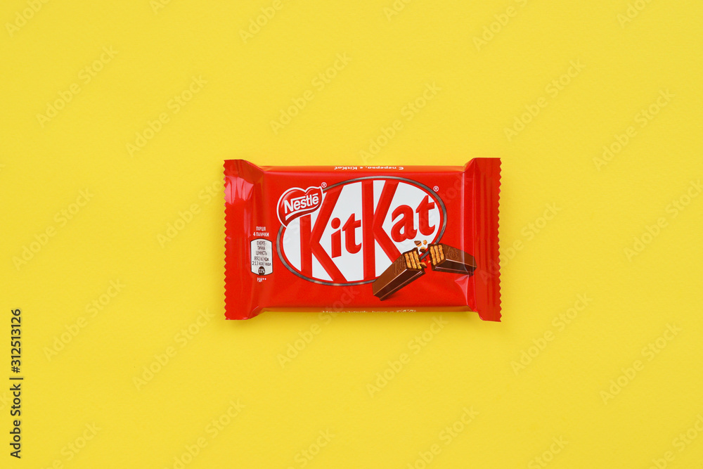 Kit Kat chocolate bar in red wrapping lies on yellow background. Kit ...