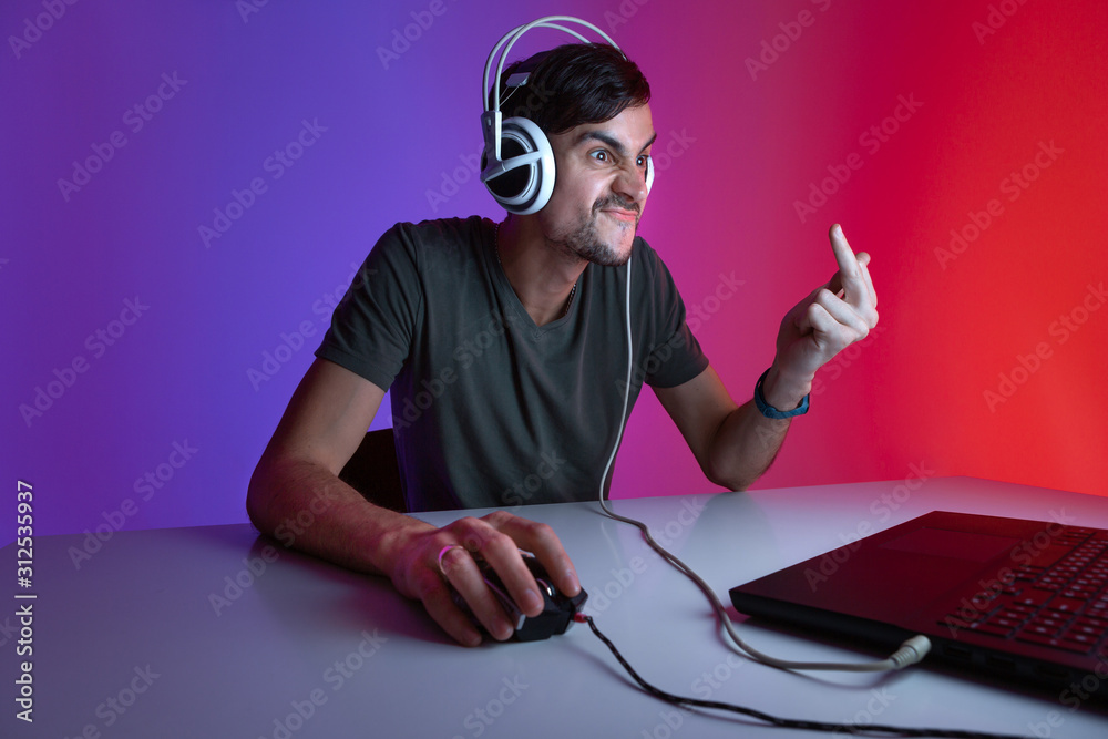Portrait of an angry gamer playing video games on computer in dark room ...