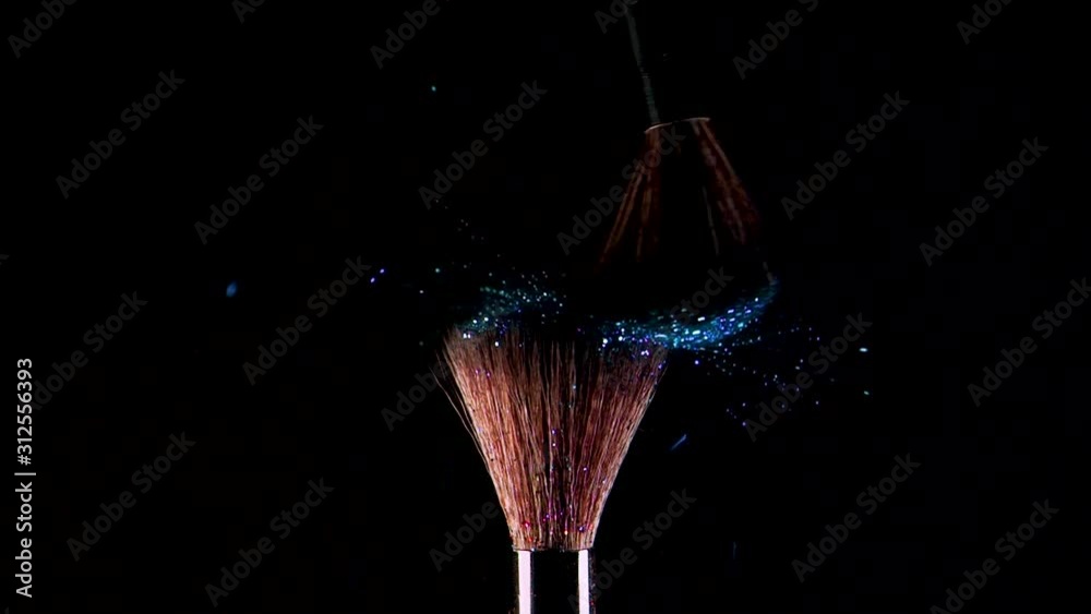 Two makeup brushes with bright eye shadow. Glitter and shadows scatter ...
