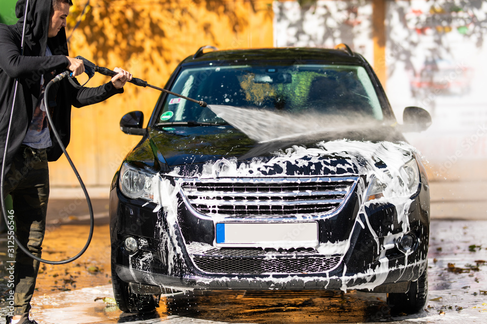 Young man washing his car in a self-service car wash station Stock ...
