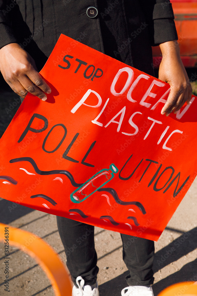 Person with placard Stop ocean plastic pollution Stock Photo | Adobe Stock