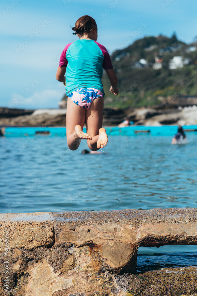 girl jumping into ocean pool Stock Photo | Adobe Stock