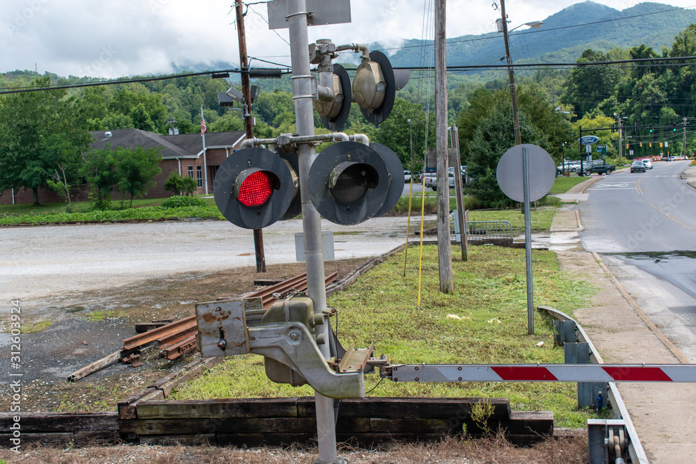 The railroad crossing signal flashes red as the train makes its way ...