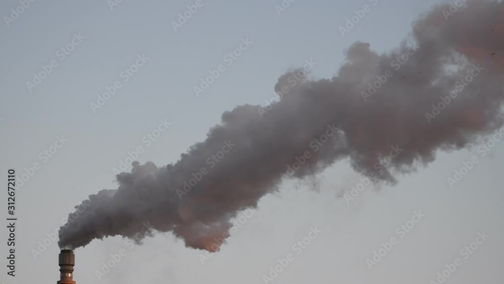 Dark hot smoke coming out of an industrial chimney of a chemical plant ...
