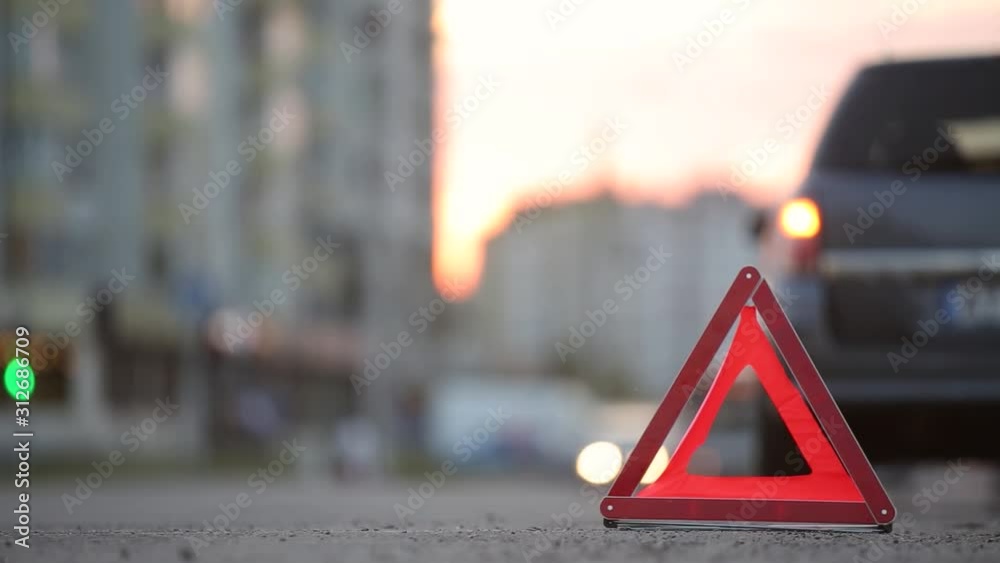 Red emergency stop sign behind broken blurred car with blinking lights ...