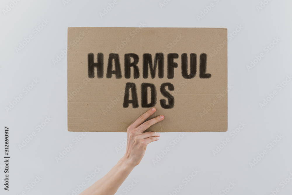 The phrase " Harmful ads " on a banner in men's hand. Human holds a ...