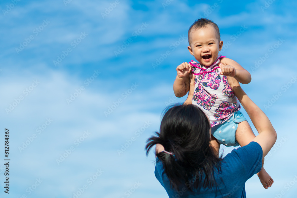 Authentic family portrait: Baby is raising to the sky by her mom's arms ...