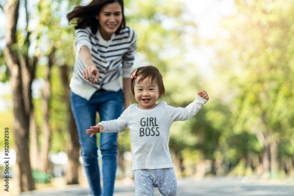 Young cute happy little Asian toddler girl running in park with mother ...
