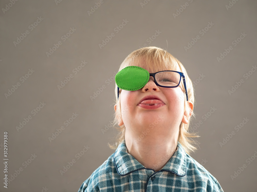 Portrait of funny child in new glasses with green spot to correct ...