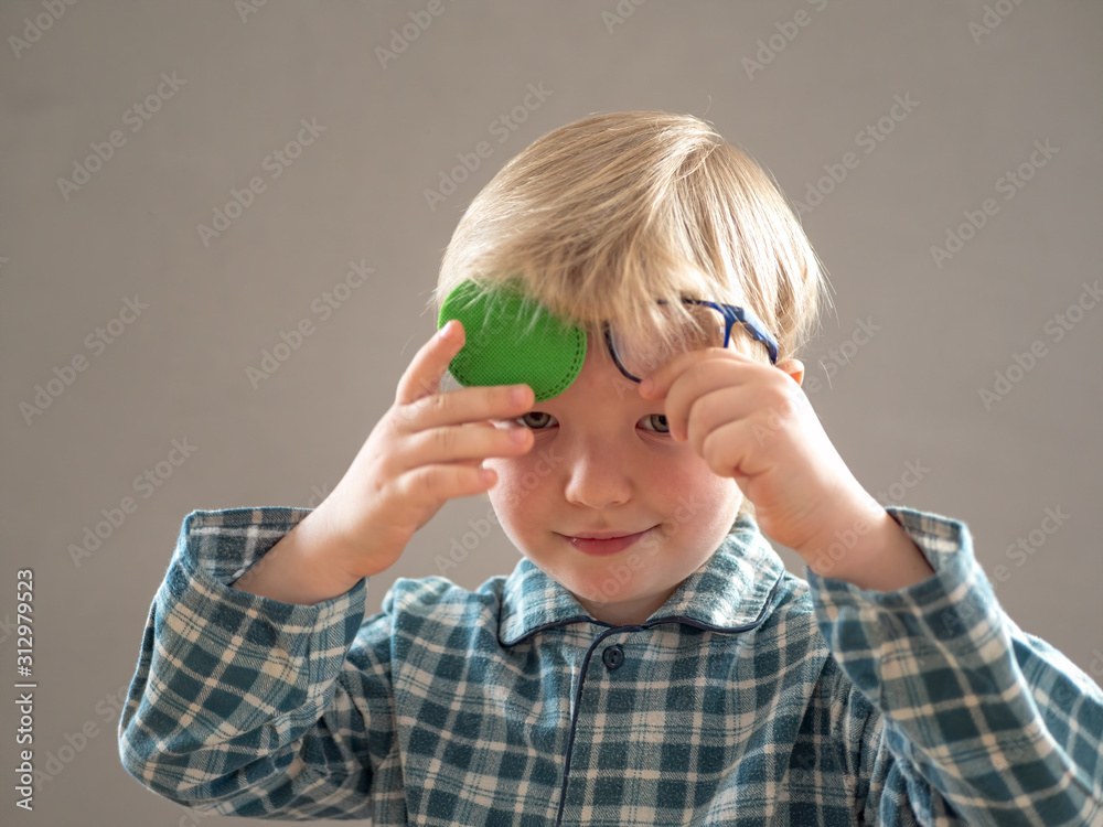 Portrait of funny child in new glasses with green spot to correct ...