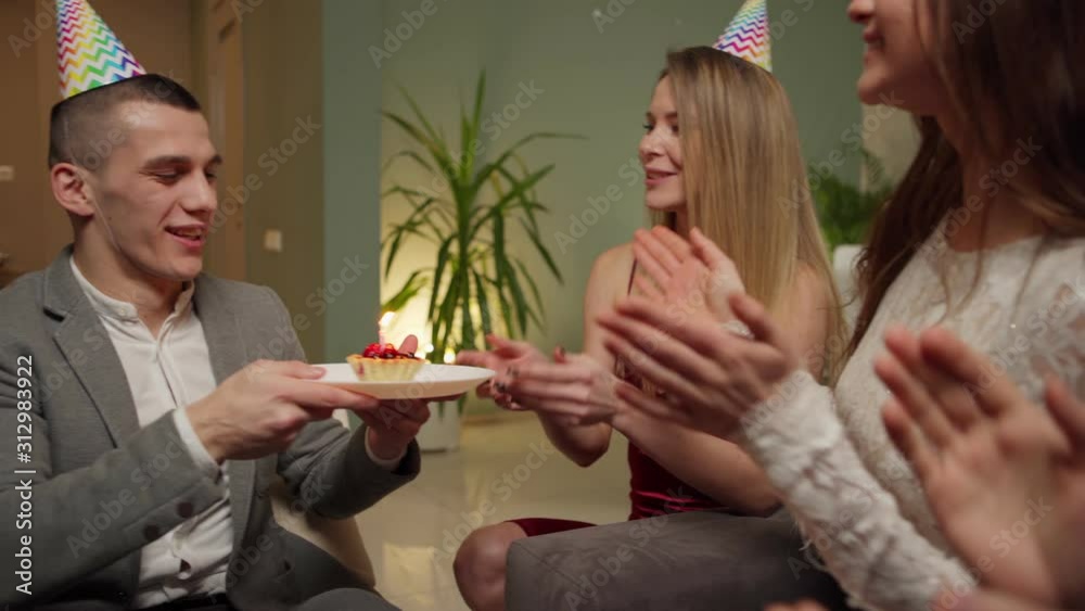 Group of happy young friends in party hats talking and applauding to ...