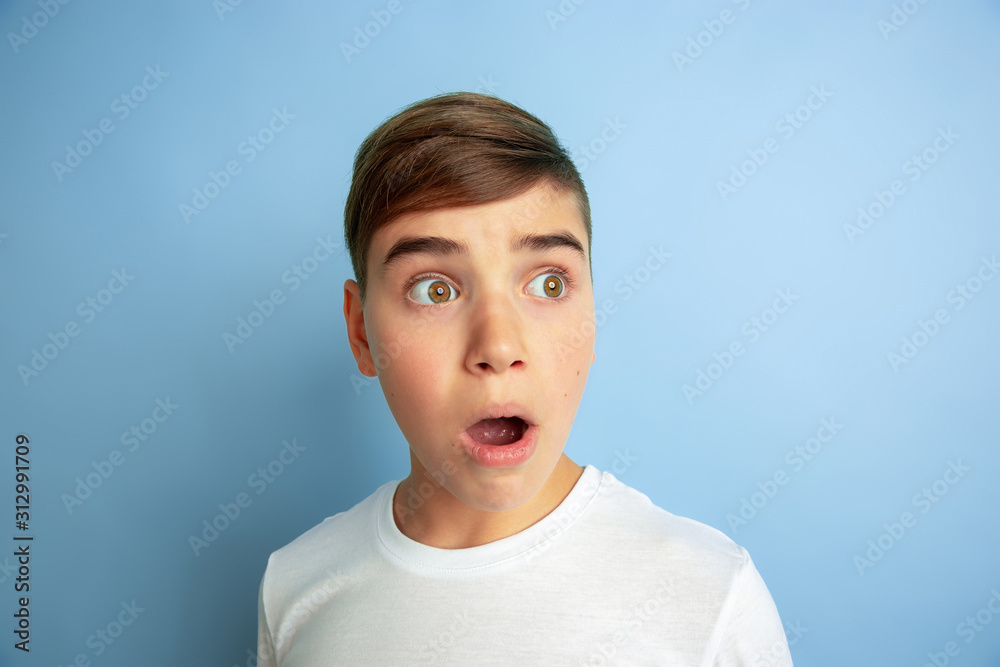 Shocked, wondered. Close up. Caucasian boy portrait isolated on blue ...