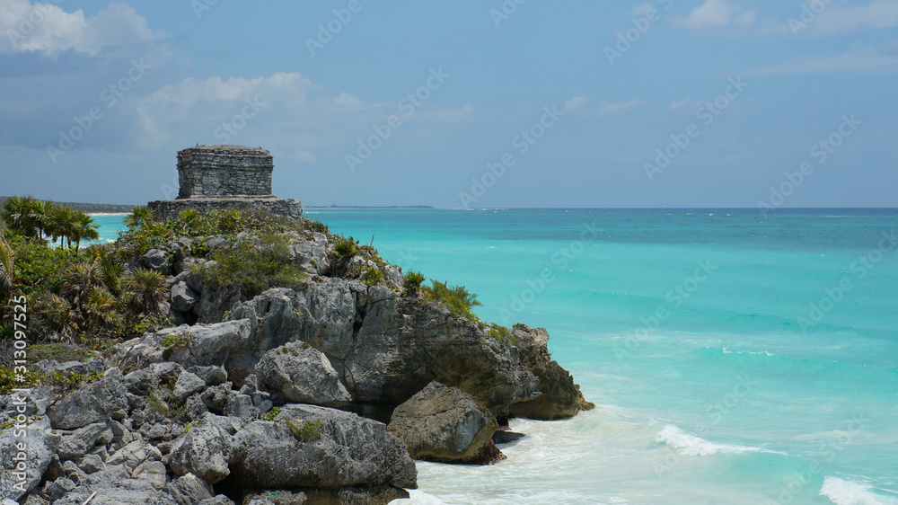 Mayan ruins tower over the coast of Caribbean sea in Tulum. It is the ...
